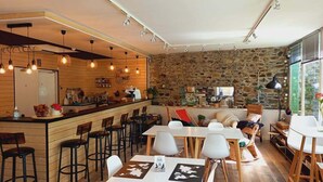 Um restaurante acolhedor com parede de pedra, balcão de madeira e área de estar com mesas e cadeiras.