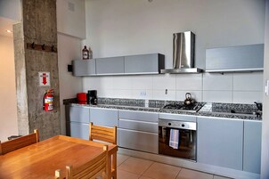 Uma cozinha moderna com armários cinzas, uma coifa de aço inoxidável, fogão a gás e forno embutido.
