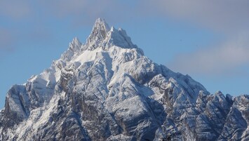 Um pico montanhoso coberto de neve, com terreno acidentado e picos afiados.