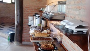 Buffet com diversas opções de comida, incluindo melancia, melão e um dispensador de ponche de frutas.