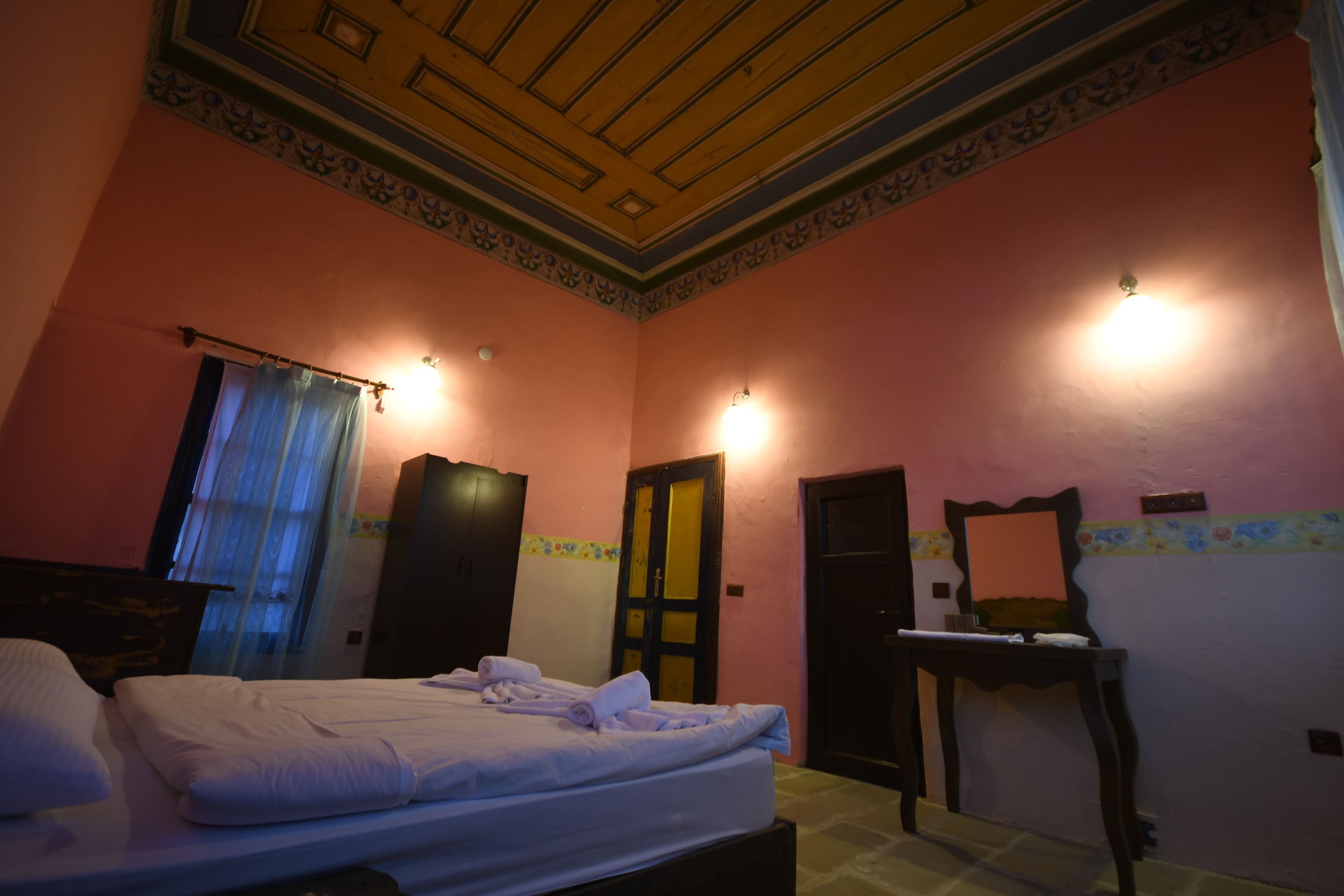 Um quarto com cama, cômoda, espelho e porta.