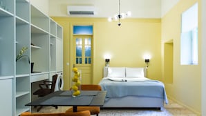 Quarto com cama, abajures, mesa com cadeiras, estante e janela.