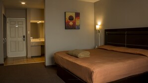 Quarto de hotel com cama, banheiro e um quadro na parede.
