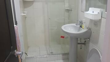 Casa de banho com sanita, lavatório e cabine de duche em vidro.