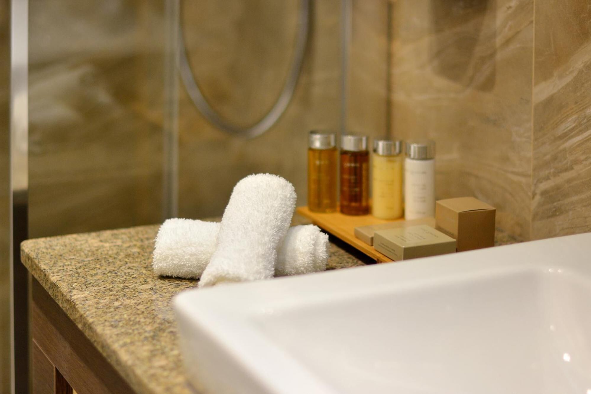 Um banheiro com bancada de granito, uma banheira branca e amenities, incluindo frascos e um sabonete.