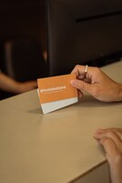 Uma mão segurando um cartão de visita com o texto @hotelesbens.