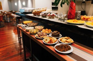 Mesa de buffet com diversos alimentos, incluindo pão, biscoitos e frutas.