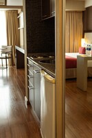 Cozinha moderna com eletrodomésticos de aço inoxidável, painel de azulejos e piso de madeira.