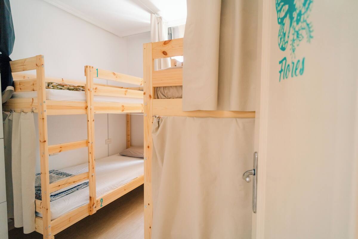 Quarto com beliche, porta e parede com padrão floral.