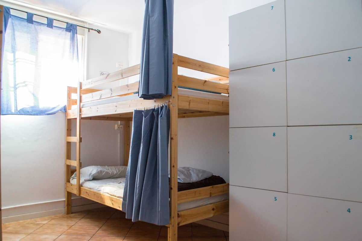 Quarto com beliche, guarda-roupa e chão revestido de azulejos.