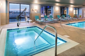 Área de piscina de hotel com duas piscinas, espreguiçadeiras e elevador de piscina.