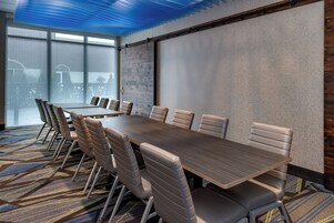 Uma sala de conferências com uma mesa comprida, várias cadeiras e uma janela grande.