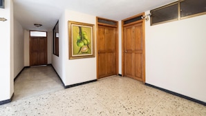 Um corredor com piso de azulejos, portas de madeira e um quadro emoldurado na parede.
