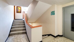 Uma escadaria com corrimão, uma porta com a placa 'Escaleras' e um quadro na parede.