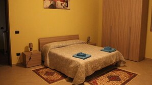 Quarto com cama, mesas de cabeceira, guarda-roupa e um quadro na parede.