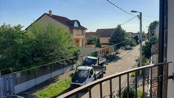 Rua residencial com casas, carros estacionados e céu claro.