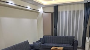 Uma sala de estar moderna com dois sofás escuros, uma mesa de centro de madeira e piso em madeira clara.