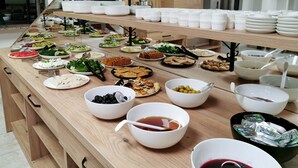 Uma mesa de buffet com diversos alimentos e recipientes, incluindo saladas, sanduíches e bebidas.