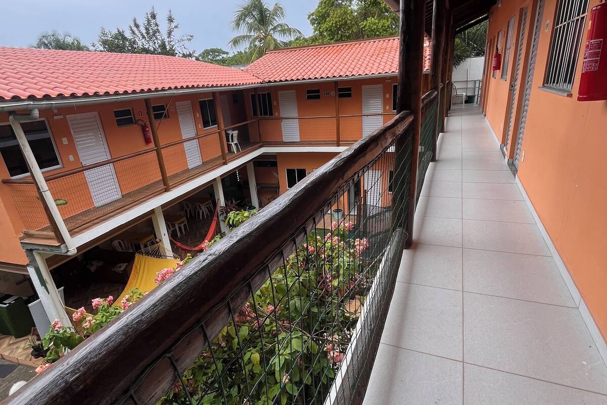 Varanda coberta com vista para um edifício com paredes laranja e telhado de telhas vermelhas.