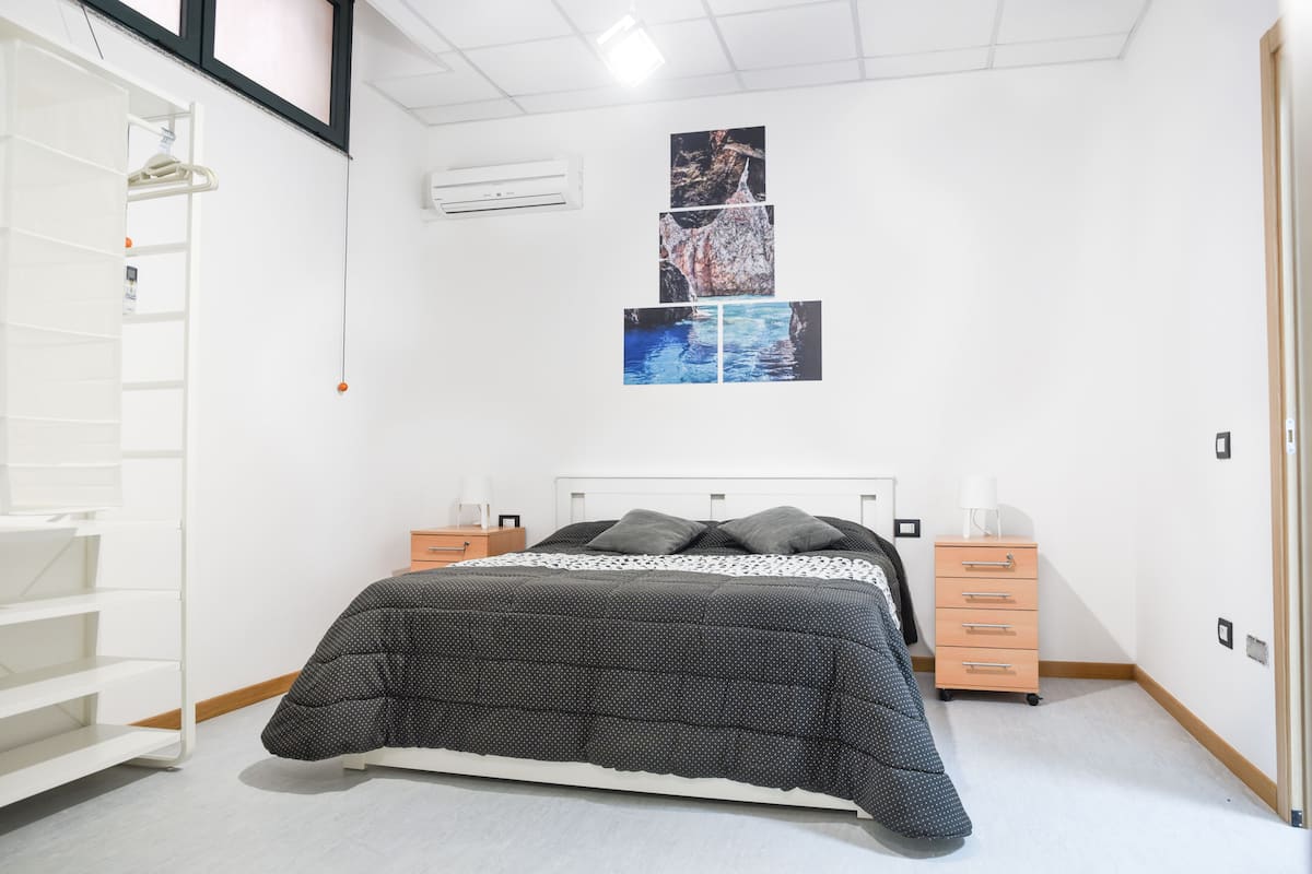Quarto com cama, guarda-roupa, penteadeira e quadros nas paredes.