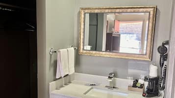 Casa de banho com lavatório, espelho, porta-toalhas e um cesto de lixo.
