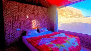 Quarto com cama, paredes estampadas e vista para uma paisagem montanhosa.