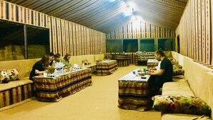 Um quarto em estilo tenda com teto alto, várias mesas e sofás.
