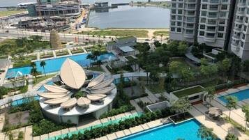 Hotel moderno com piscina central, rodeado por vegetação exuberante e vista para um rio.