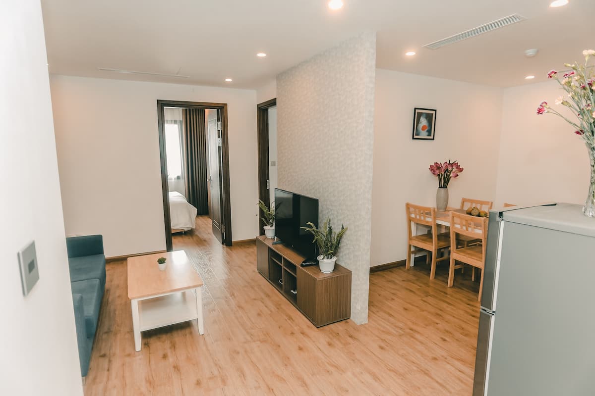 Uma sala de estar moderna com televisão de tela plana, móveis de madeira e um espaço para refeições.