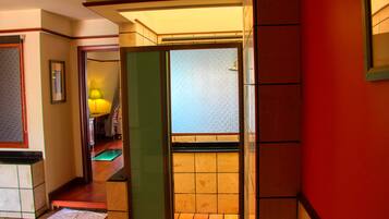 Um corredor com vista para um corpo de água através de uma porta de vidro, piso ladrilhado e parede vermelha.