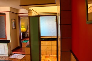 Um corredor com vista para um corpo de água através de uma porta de vidro, piso ladrilhado e parede vermelha.