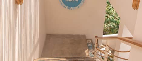 Uma escadaria com azulejos estampados que leva a um quarto com a placa 'SEASTA'.