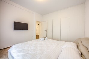 Quarto de hotel com uma cama, televisão de tela plana na parede e um guarda-roupa com portas de correr.