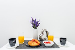 Disposição para o café da manhã com croissants, morangos e suco de laranja sobre uma mesa.