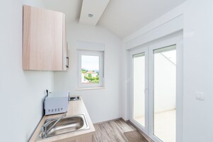 Uma cozinha moderna com micro-ondas embutido, pia e janela com vista para uma área residencial.