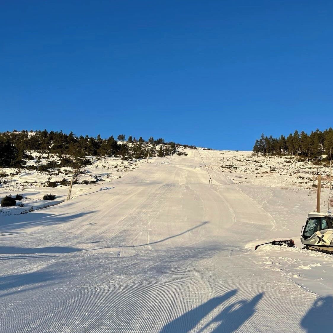 Uma estrada coberta de neve, com um veículo estacionado à direita.