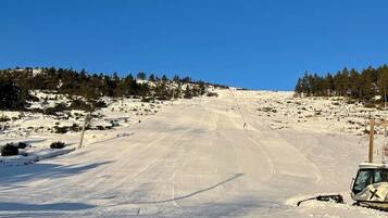 Uma estrada coberta de neve, com um veículo estacionado à direita.