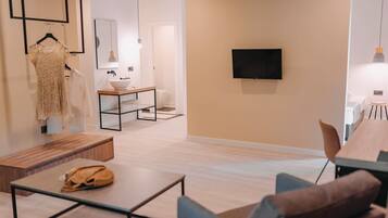 Uma sala de estar moderna com um sofá, uma mesa de centro e uma TV fixada na parede.
