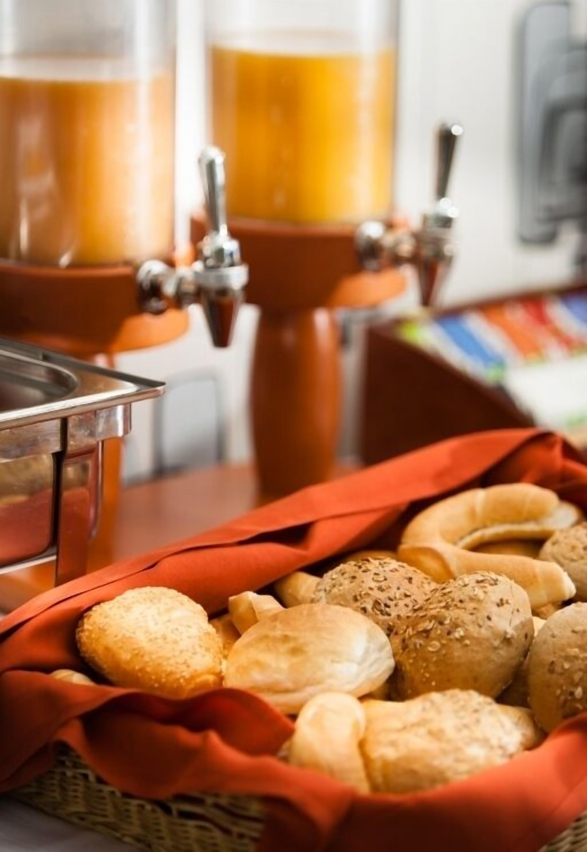 Mesa de buffet com diversos tipos de pão e uma torneira de cerveja ao fundo.