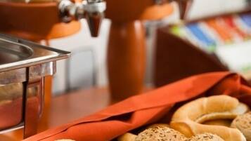 Mesa de buffet com diversos tipos de pão e uma torneira de cerveja ao fundo.