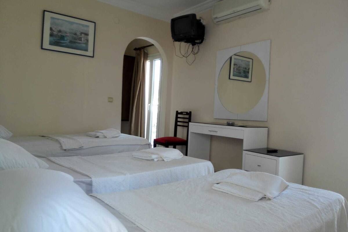 Quarto de hotel com duas camas, uma escrivaninha, uma cadeira e um espelho.