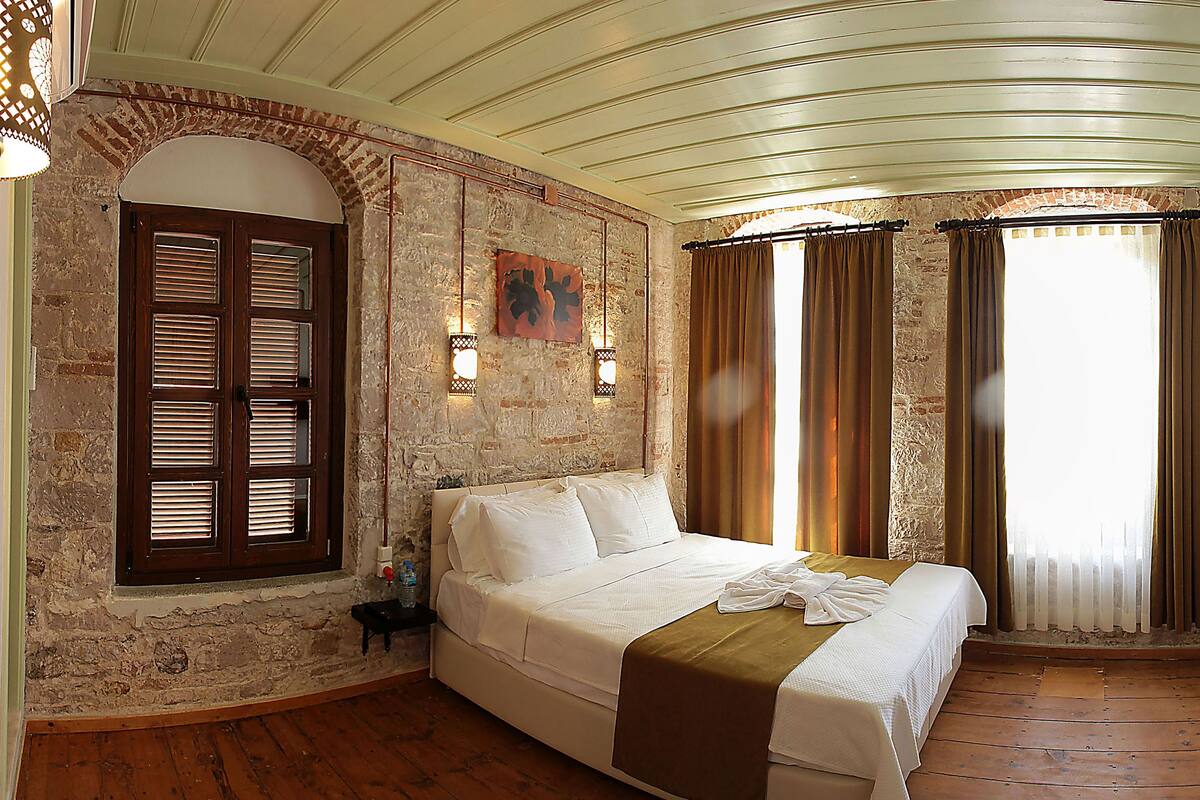Quarto com cama, parede de tijolos, piso de madeira e porta.