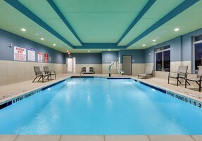 Piscina interna com água cristalina, linhas de profundidade demarcadas e cadeira do salva-vidas.