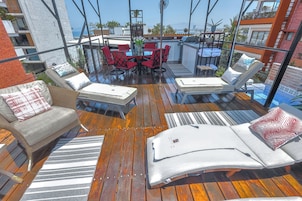 Terraço no telhado com área de estar ao ar livre, uma mesa e vista para a cidade.