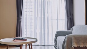Uma sala de estar moderna com uma mesa redonda, um sofá e vista através de cortinas leves.