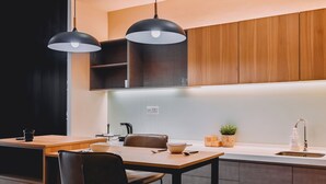Uma cozinha moderna com armários de madeira, uma mesa de jantar e duas luminárias pendentes.