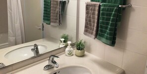 Um banheiro com pia, espelho, porta-toalhas e duas plantas em vasos.