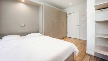 Quarto de hotel moderno com uma cama grande, um guarda-roupa e uma estante embutida.