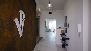 Interior moderno com piso de mármore, balcão de recepção em madeira, luminária pendente e quadros nas paredes.