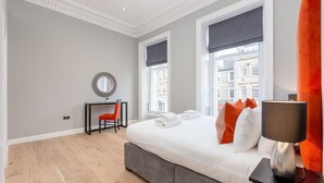 Quarto de hotel moderno com uma cama grande, uma escrivaninha e uma cadeira.